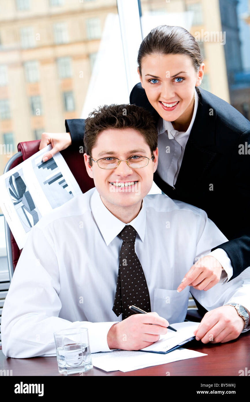 Portrait of two business partners looking at camera with happy smiles ...