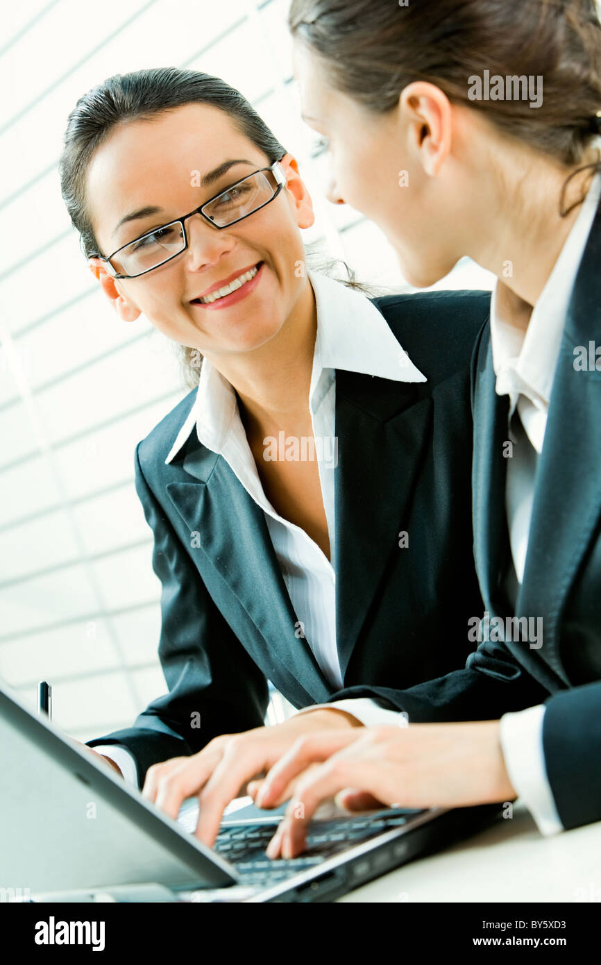 Portrait of business woman with glasses gazing at her colleague and ...