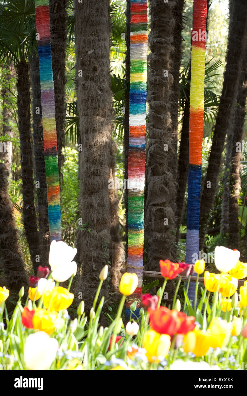 painted tree trunks as background to vari-colored tulips in Andre ...