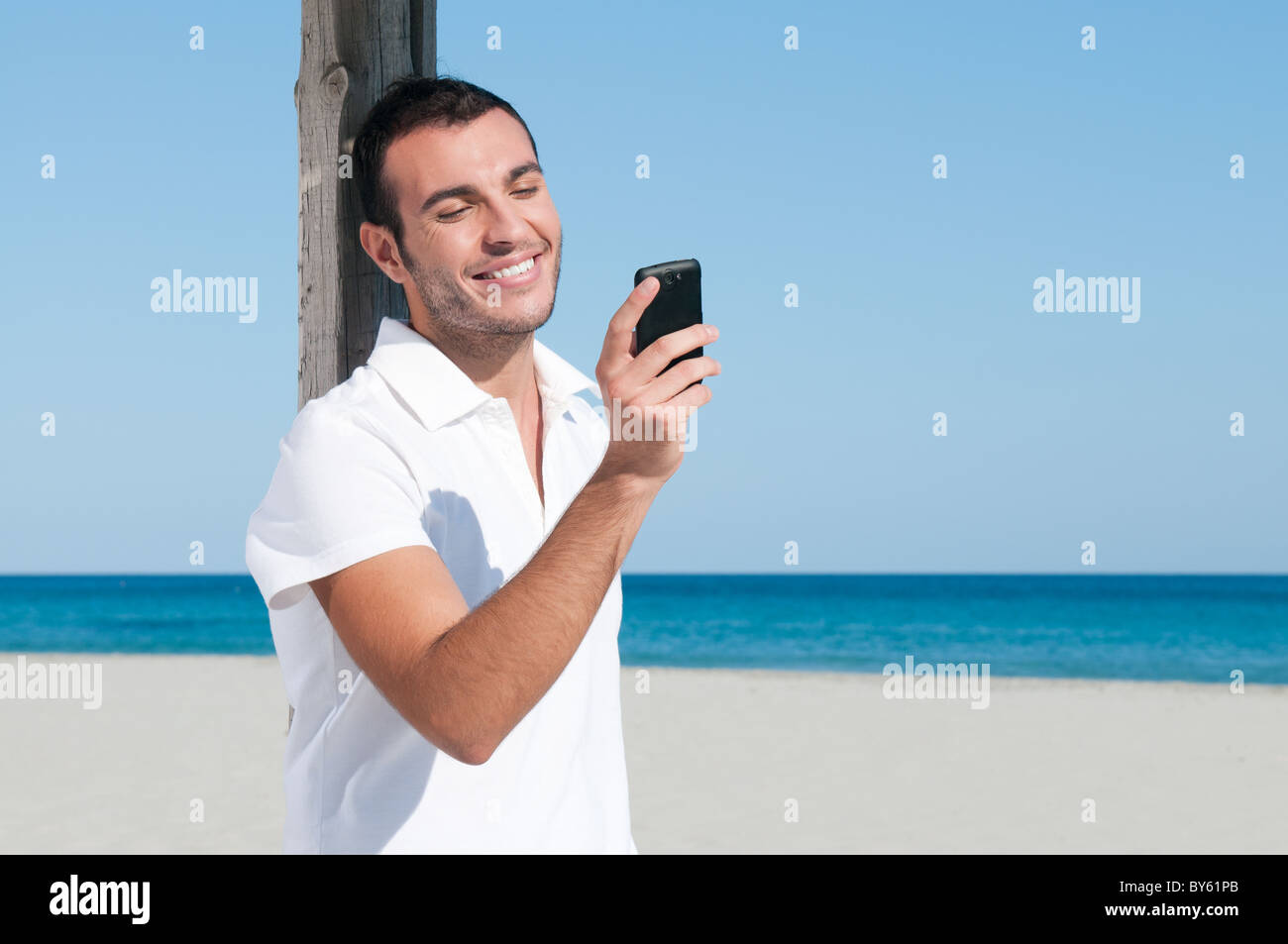 Happy smiling guy surfing the net and text messaging with his smart ...