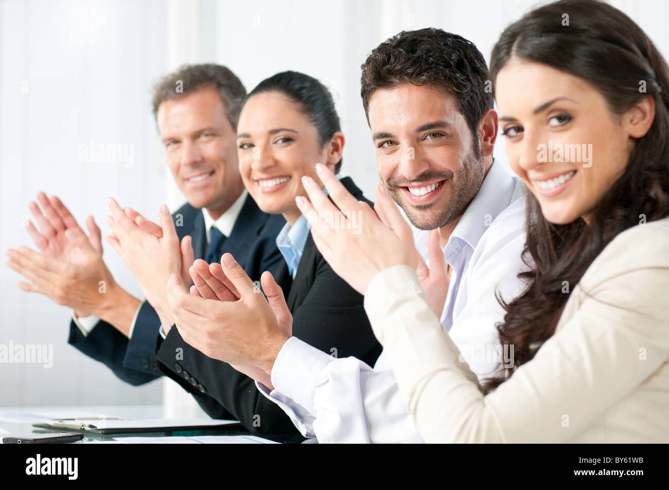 Happy smilng business team clapping hands and looking at camera in ...