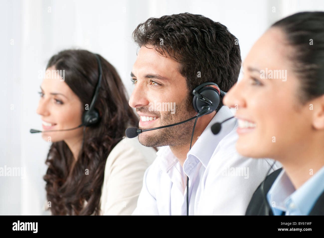 Happy smiling young man with headset in a modern call center with ...