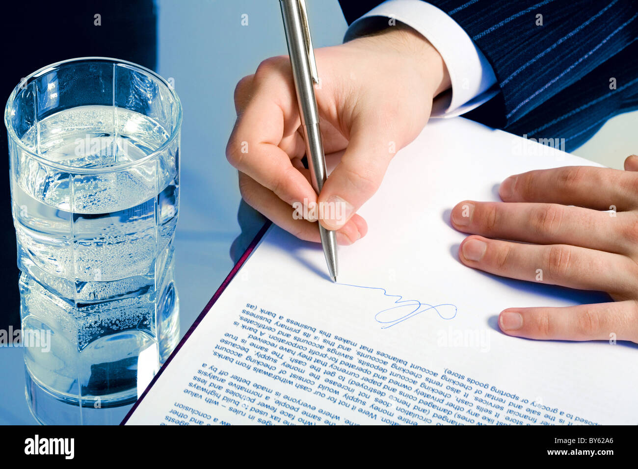 Horizontal photo of a businessman’s hands signing a contract with a ...