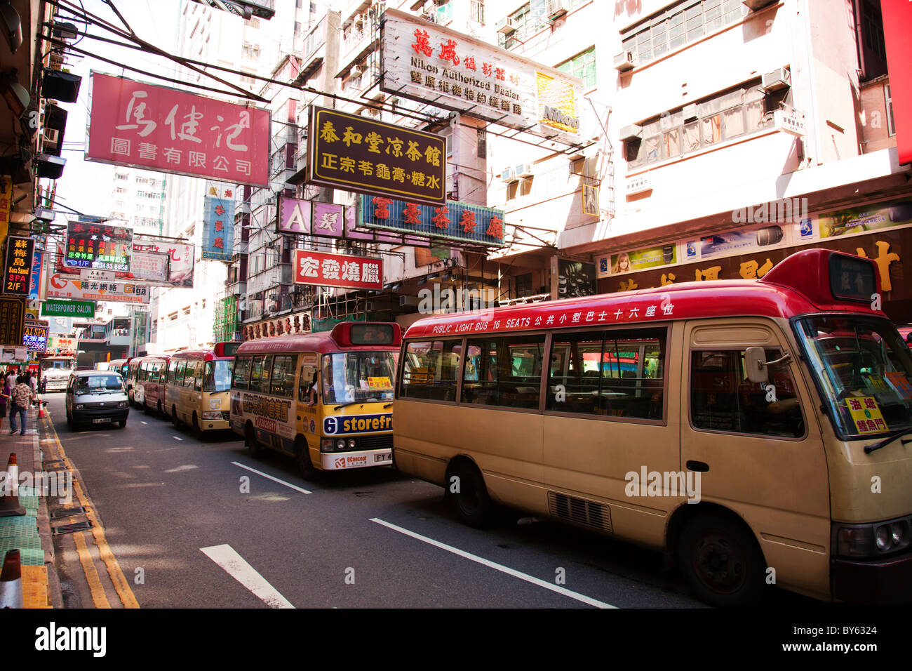 Kowloon, Hong Kong public light busses on a typical street with shop ...