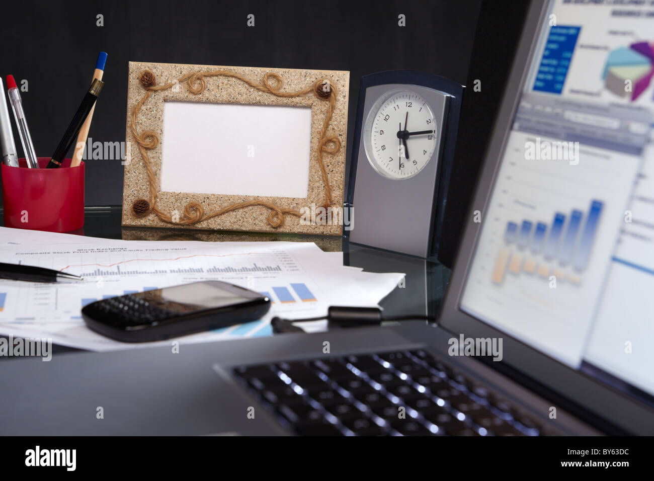 Office desk full of stuff: laptop, clock, document, blank frame and ...