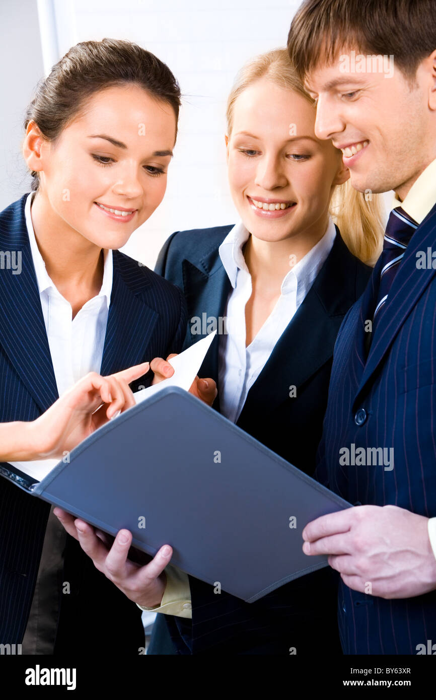Team of three people discussing an important document at business ...