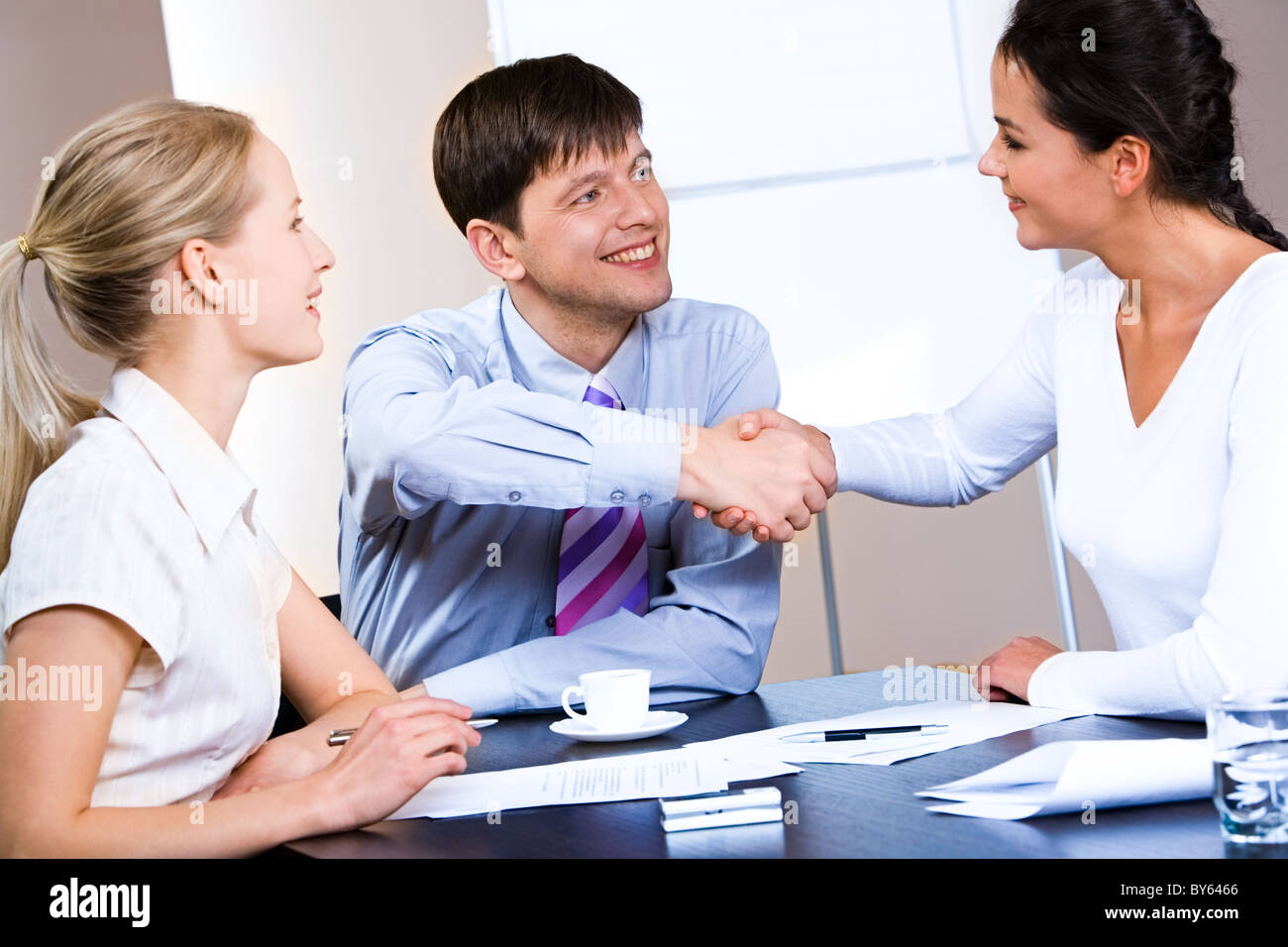 Portrait of woman and man concluding a bargain at business meeting ...
