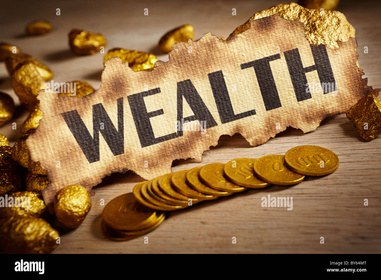 Wealth written on vintage paper and stack of gold coins and gold rocks ...