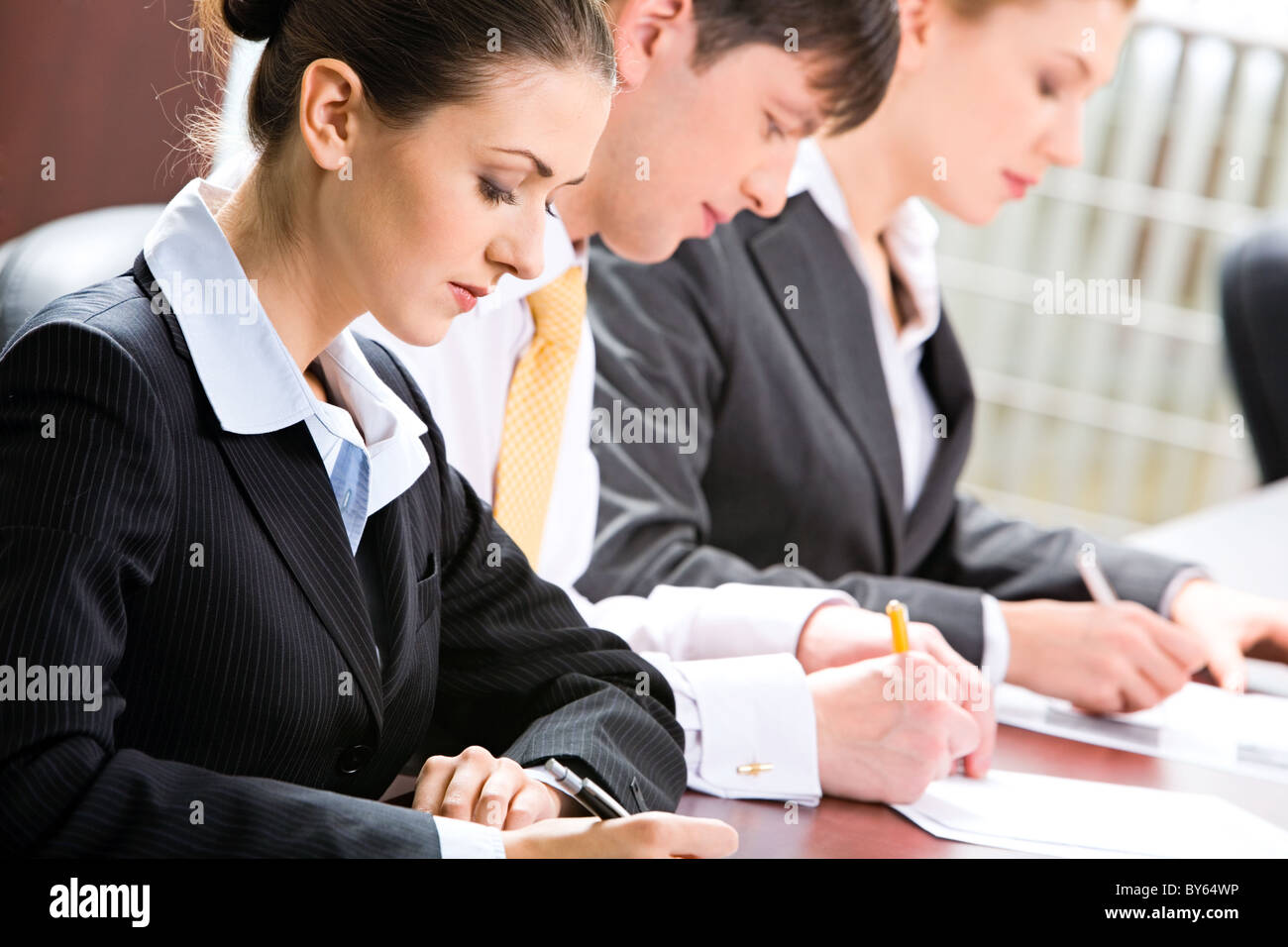 Business people with serious faces writing something on the paper Stock ...
