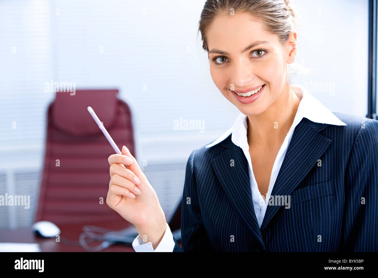 Portrait of smiling business woman holding a pen in a working ...