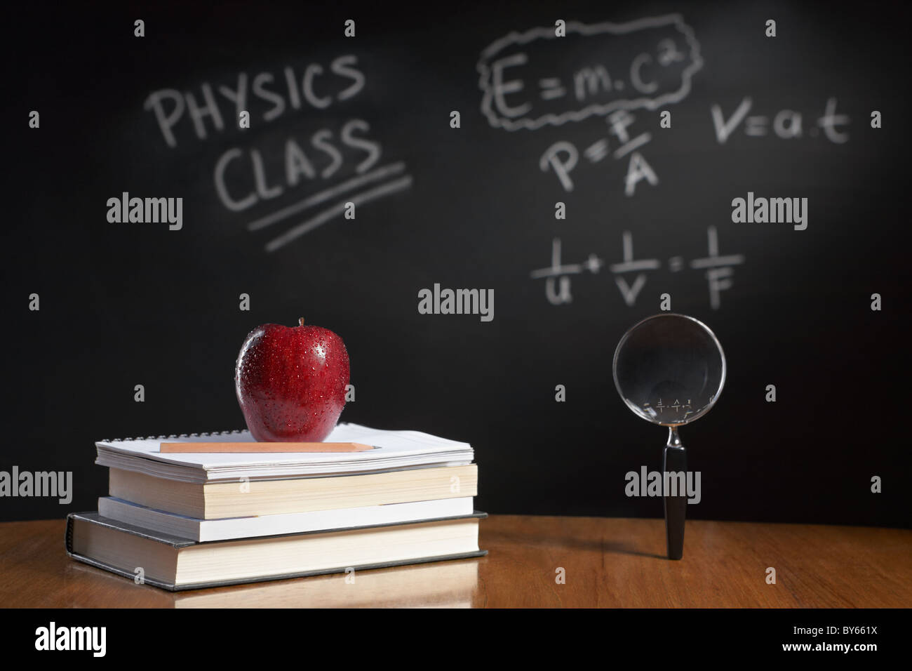 Physics class concept with red apple on pile of books and magnifying ...
