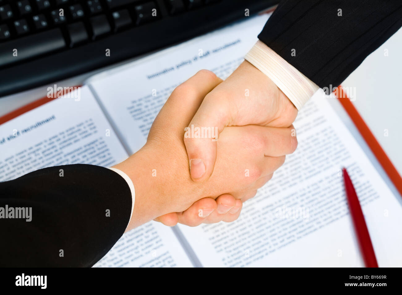 View of handshake over contract with pen in the background Stock Photo ...