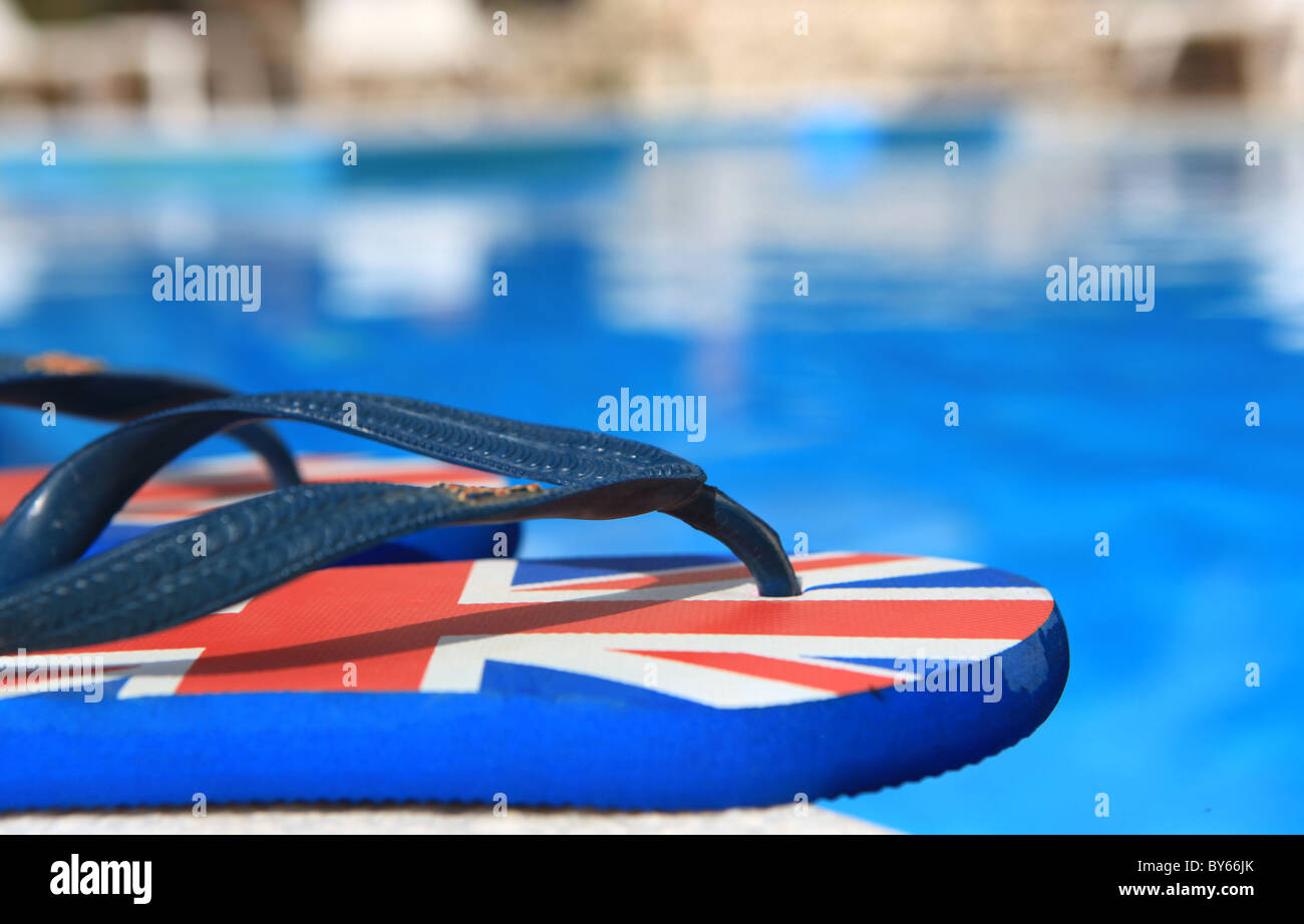 Flip flops beside a swimming pool with a UK Union Jack flag printed on ...