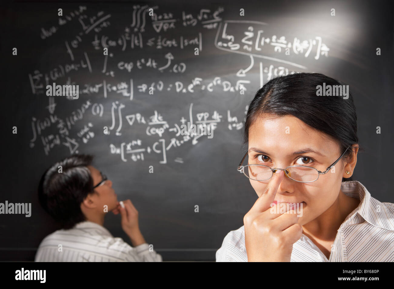 Female student pose with male student trying to solve the equation on ...