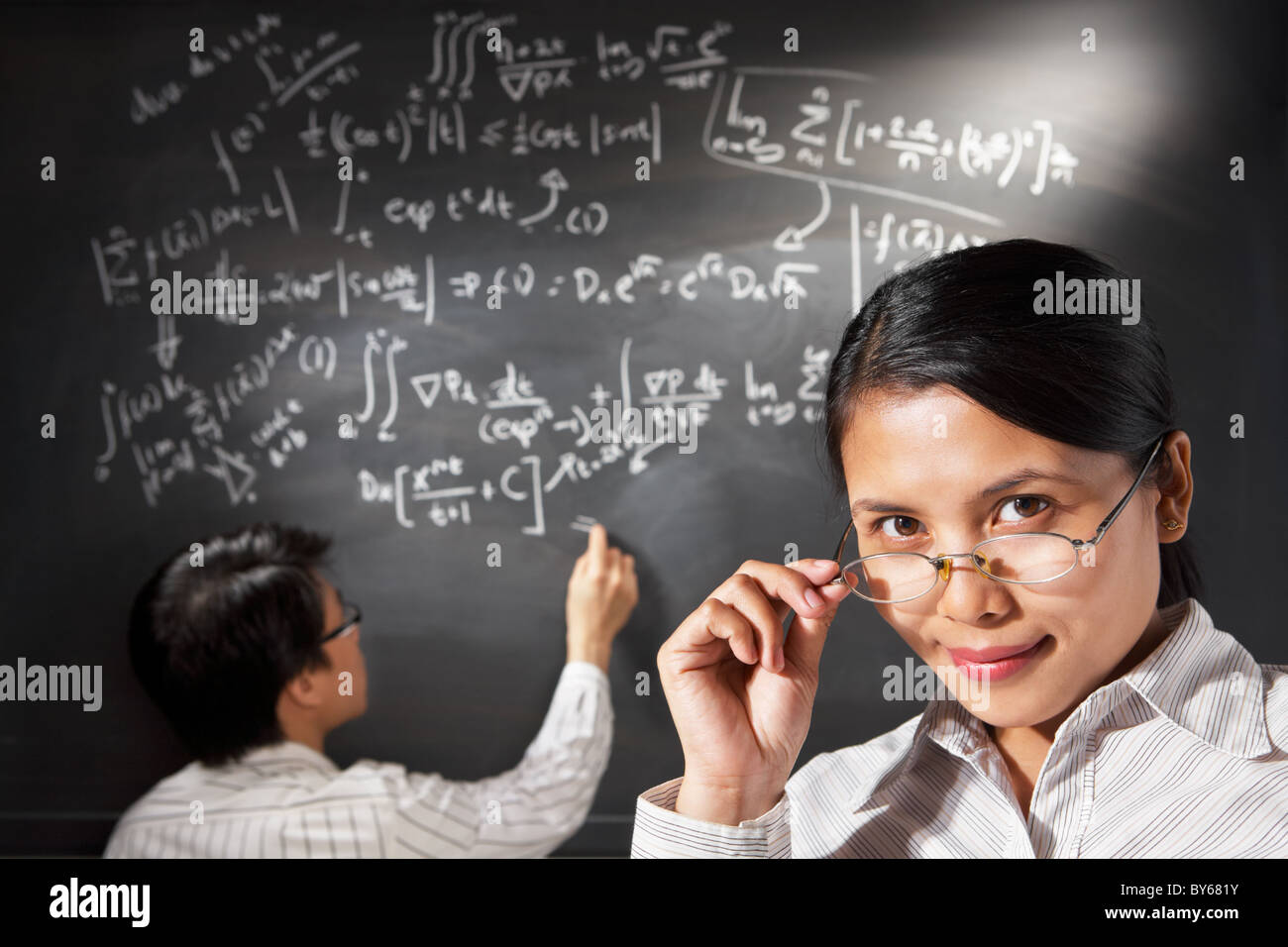 Female student pose with male student trying to solve the equation on ...