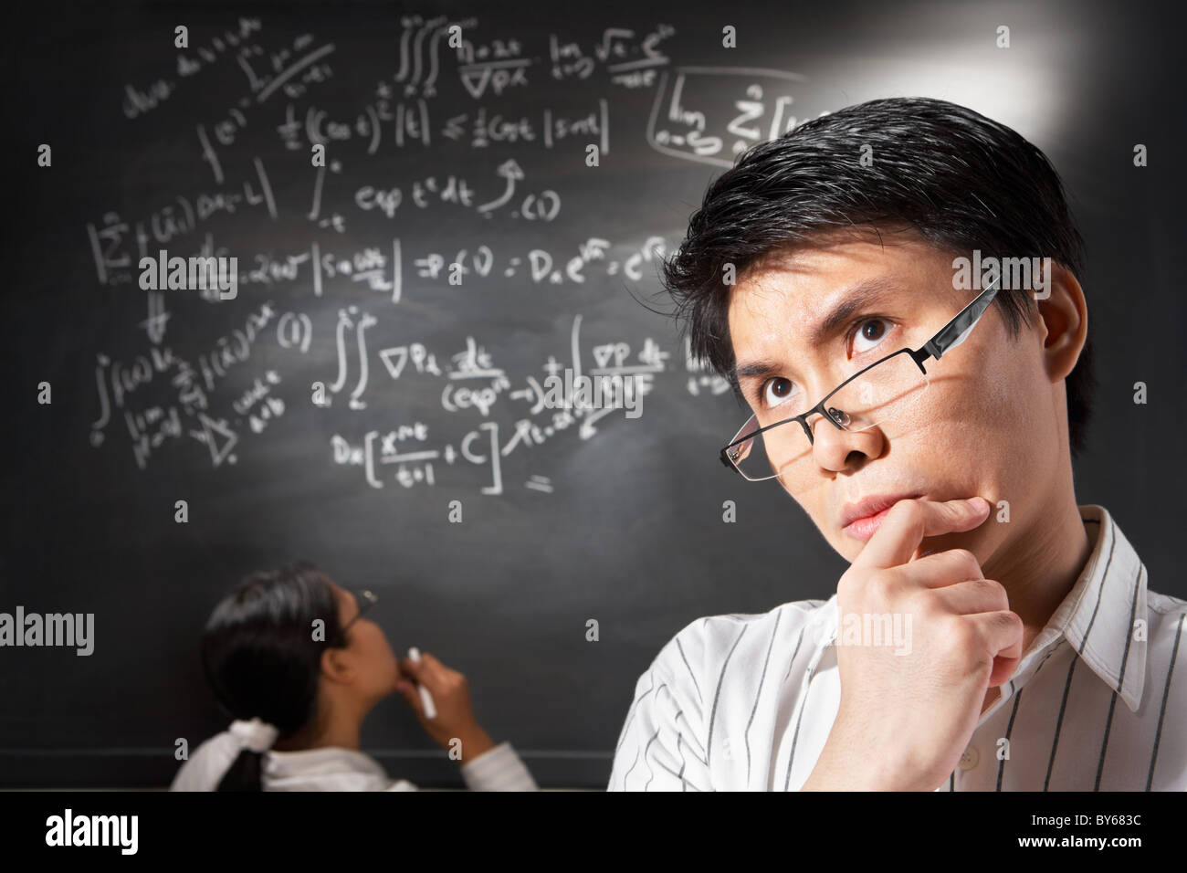 Male student pose with female student trying to solve the equation on ...