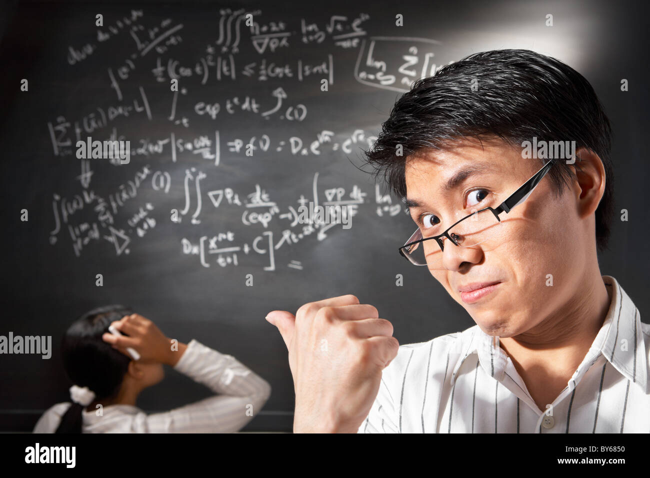Male student pose with female student trying to solve the equation on ...