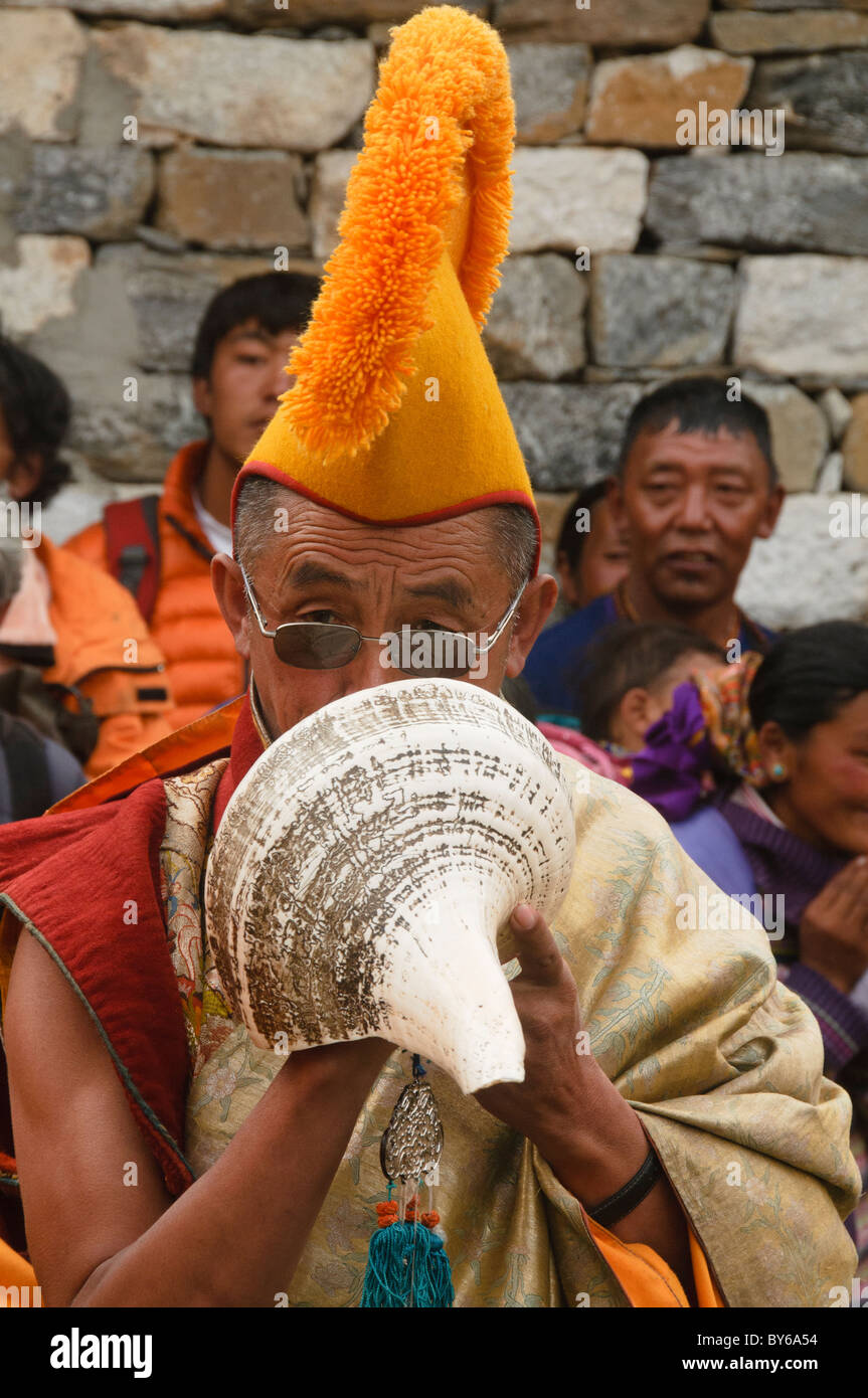 yellow hat Gelugpa monk blowing a conch shell at the Mani Rimdu ...