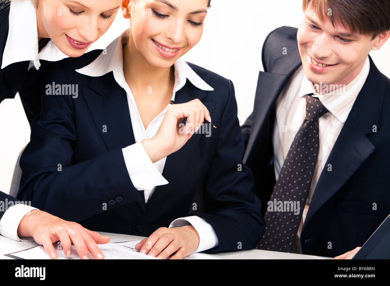 Portrait of business partners sitting around table and looking at ...