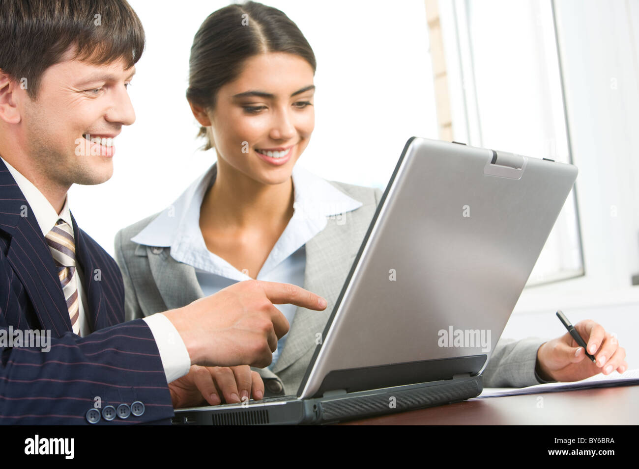 Photo of successful man pointing at laptop monitor while his partner ...
