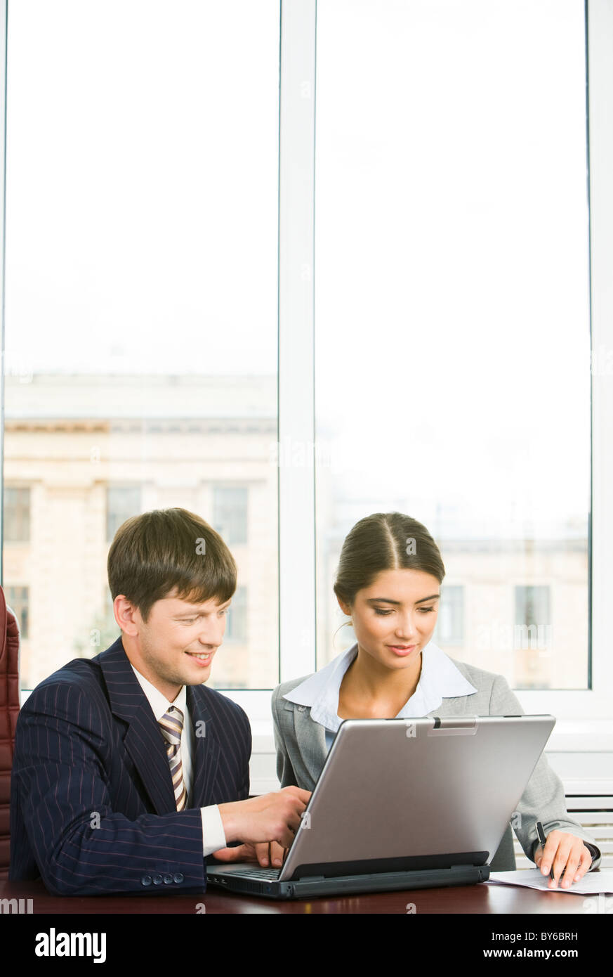 Vertical image of two working people on background of window in office ...