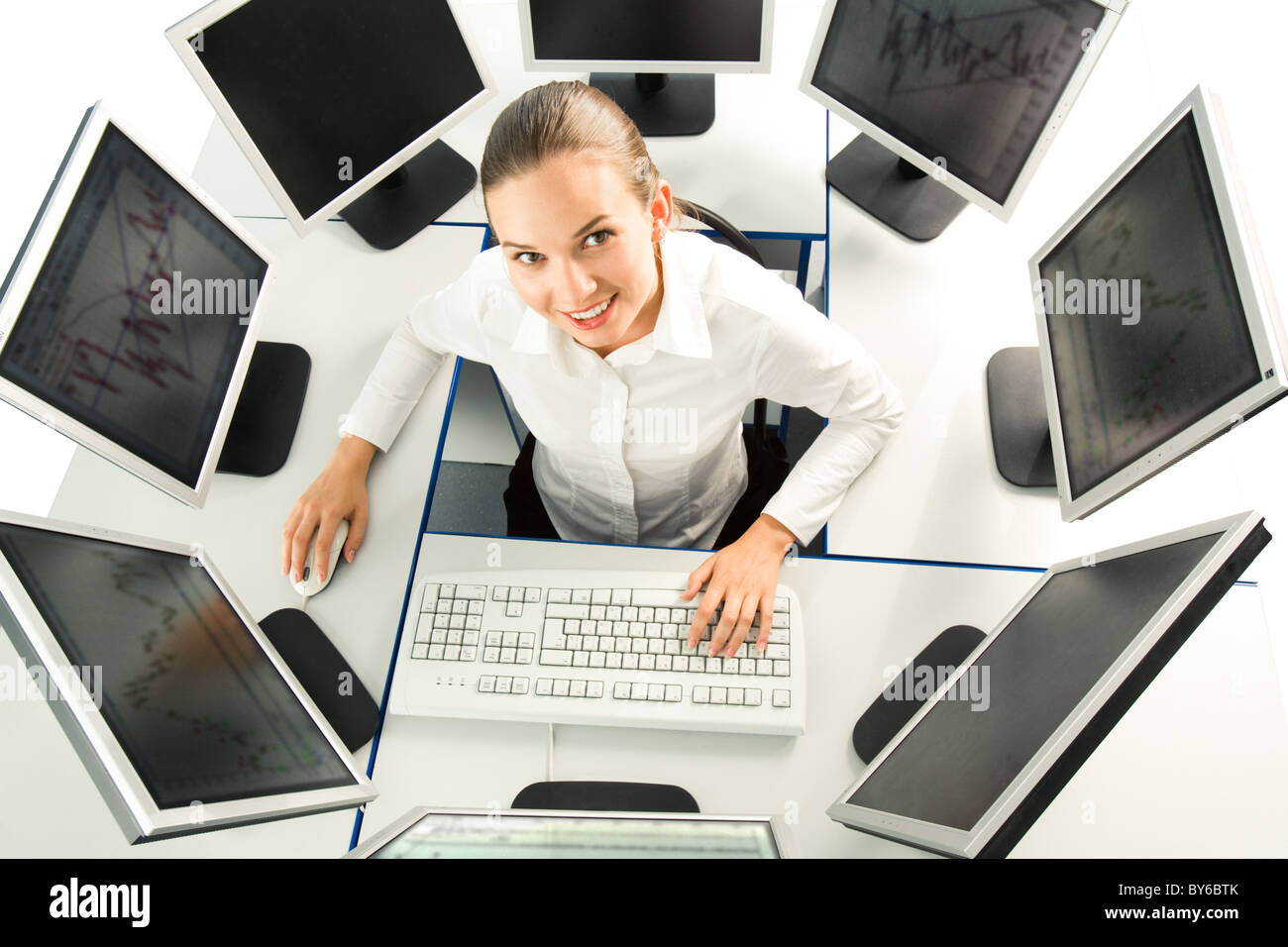 View from above of businesswoman sitting at desk with several computers ...