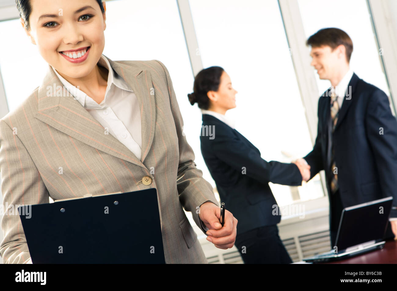 Portrait of pretty secretary with smile on the background of handshake ...