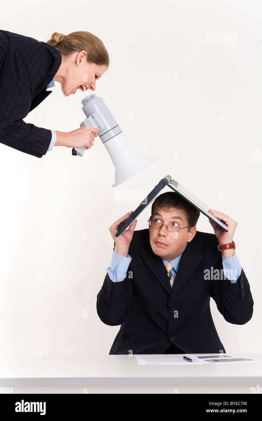 Portrait of man with laptop on head scared by woman shouting through ...
