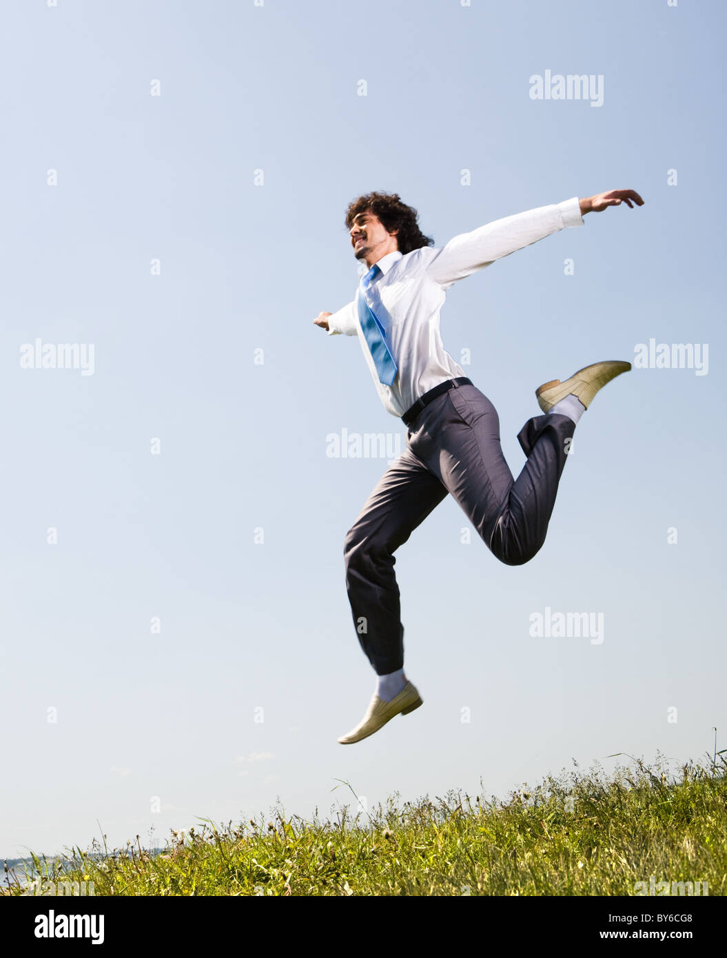 Portrait of happy employee jumping and raising hands Stock Photo - Alamy