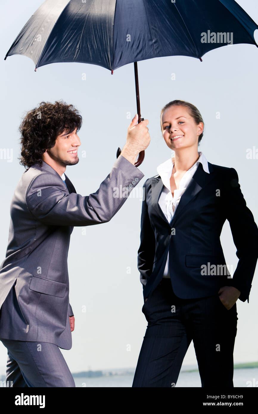 Portrait of two successful business people under umbrella together ...