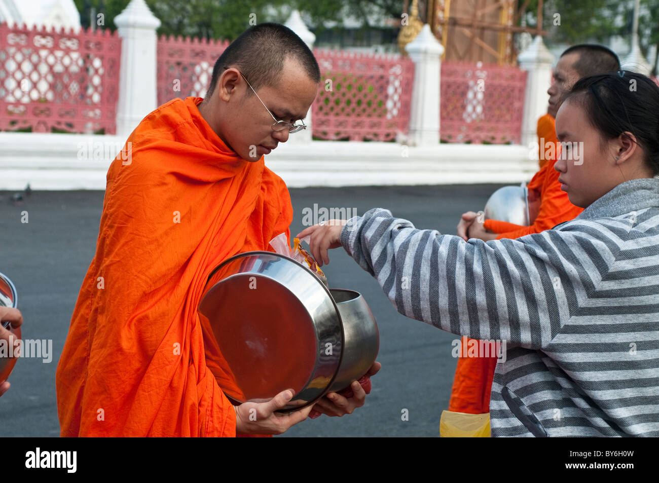 Monks receiving alms from a girl in front of Wat Benjamabophit, Bangkok ...