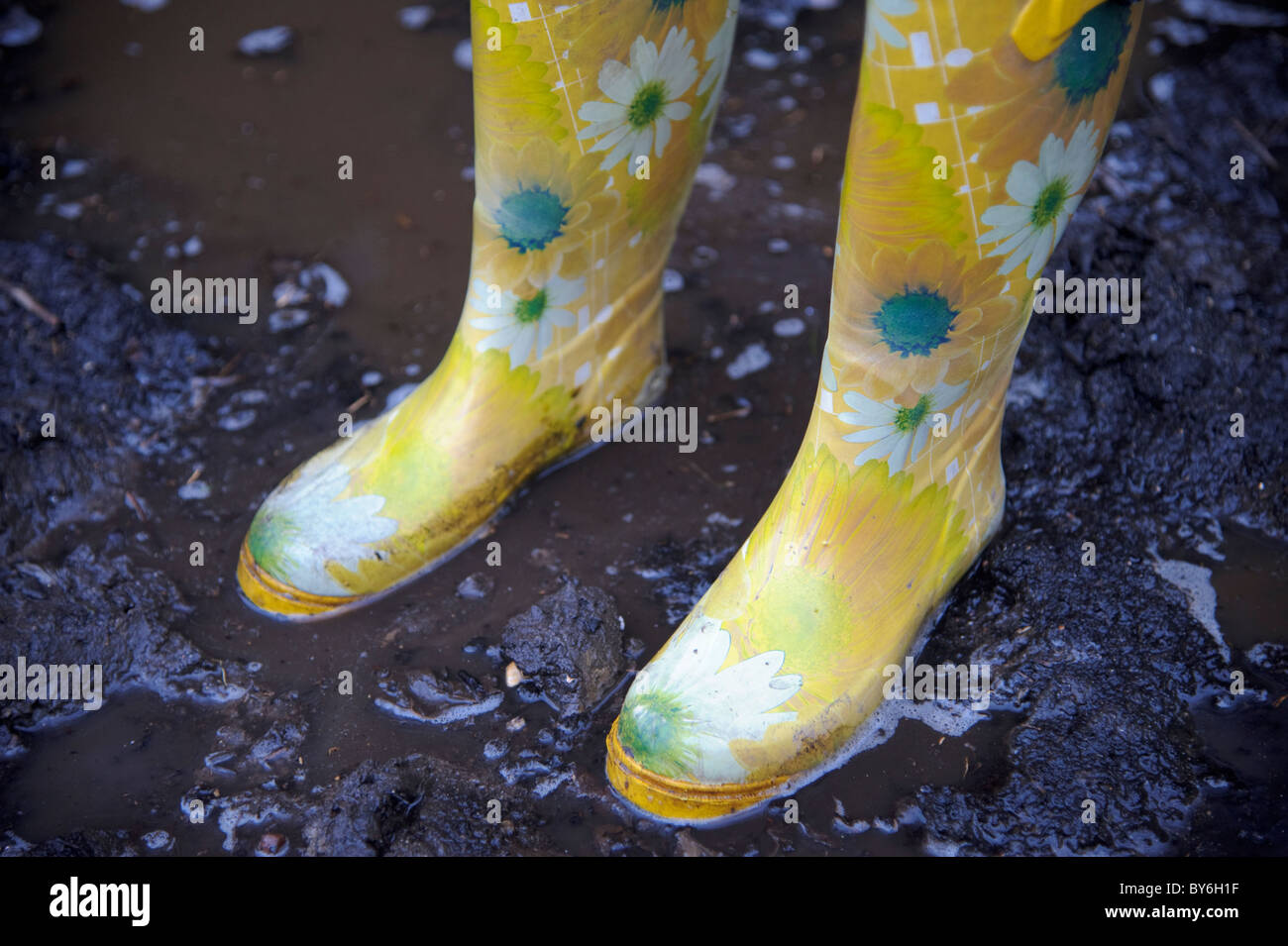 Pair of yellow rubber boots standing in a muddy puddle Stock Photo - Alamy