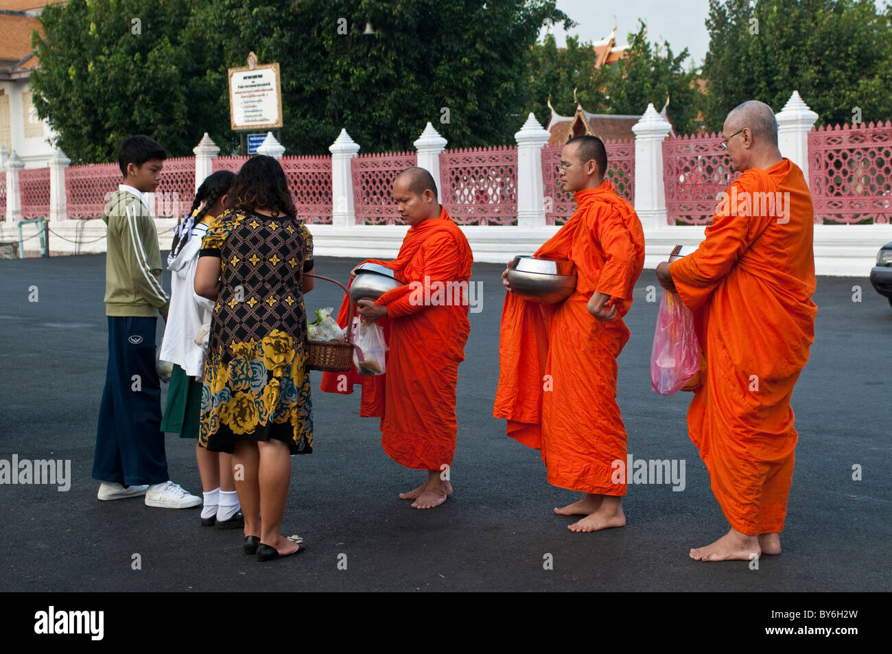 Monks receiving alms from merit-makers in front of Wat Benjamabophit ...
