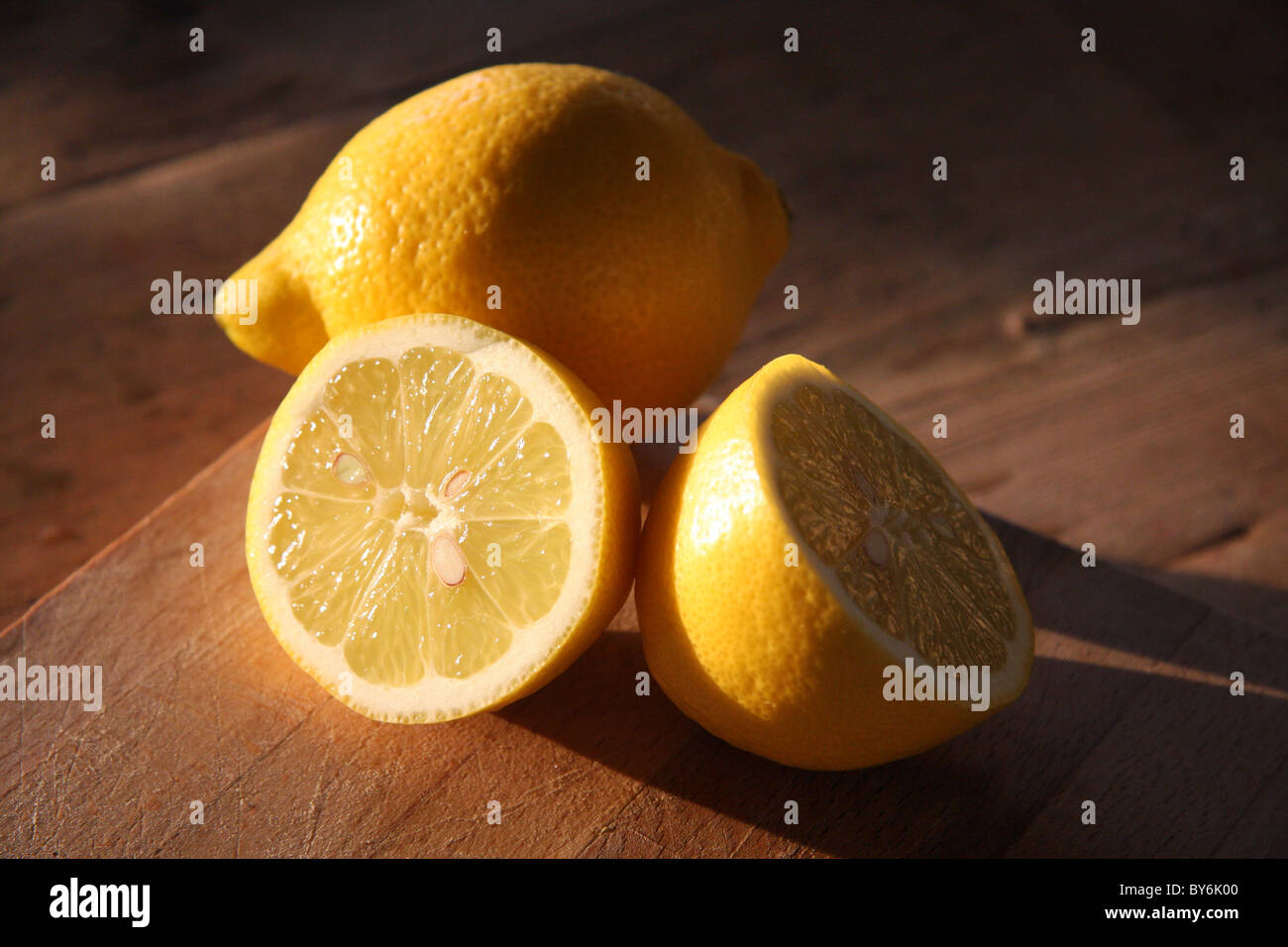 cut lemon and an uncut lemon on a chopping board Stock Photo - Alamy