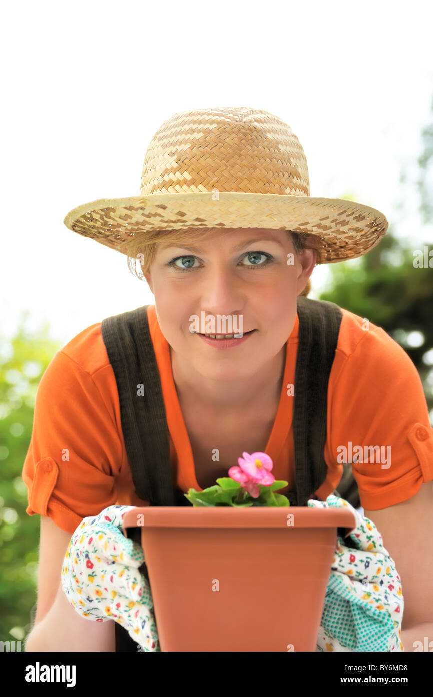 Happy young woman gardening - potting Begonia flowers Stock Photo - Alamy