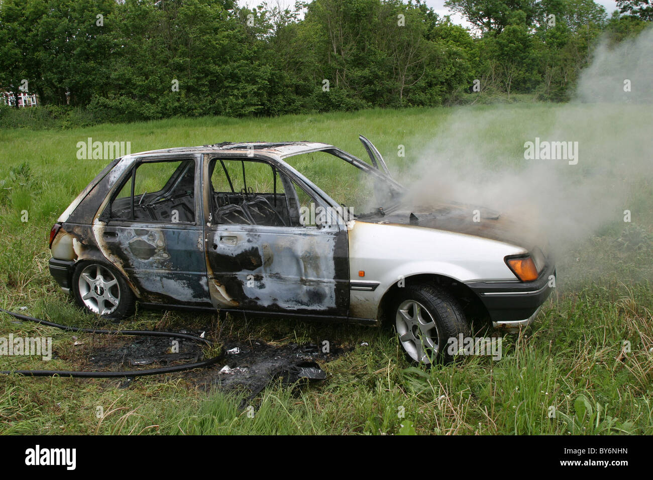 Fire damaged car left in a field Stock Photo - Alamy