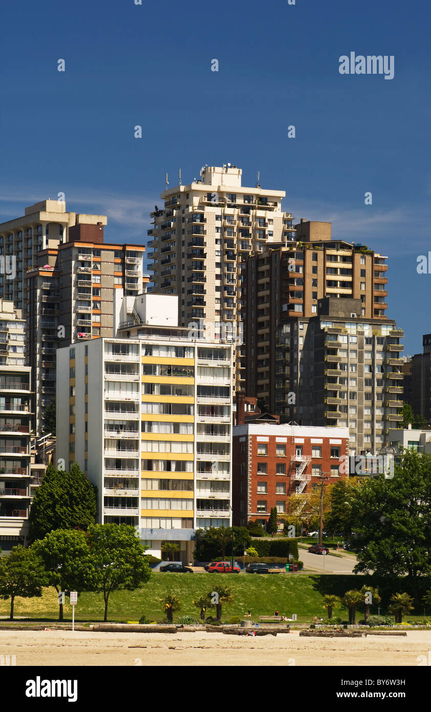A group of apartments stand tall by some green space and a sandy area ...