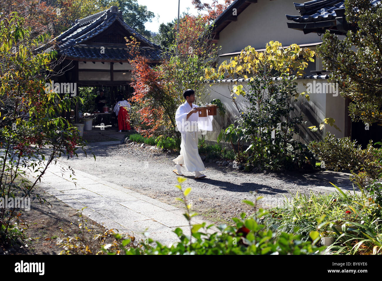 Shintoist carrying tray of tea in garden of temple, Kyoto, Honshu ...