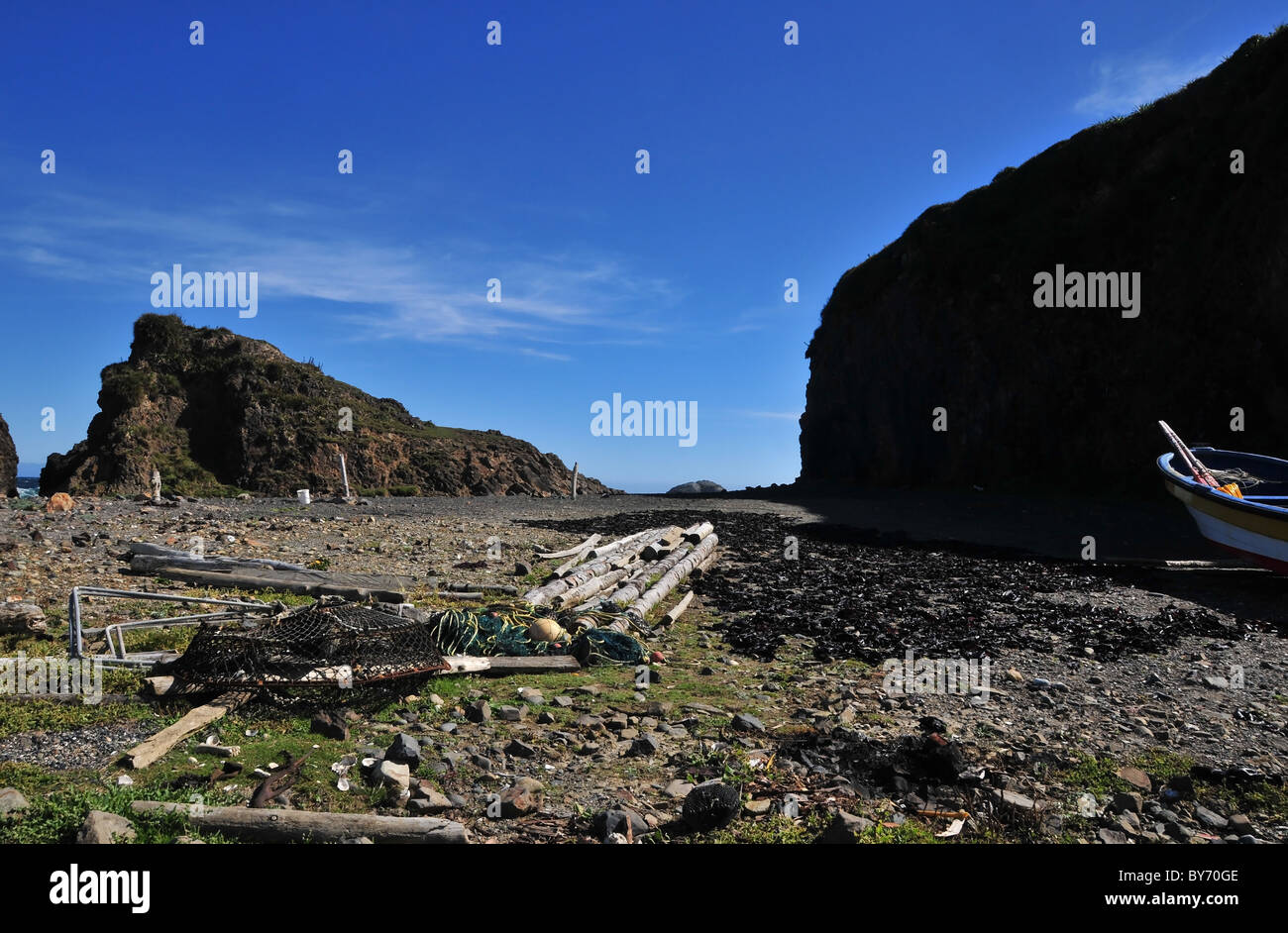 Blue sky beach platform, seaweed and fishing tackle, between basalt ...