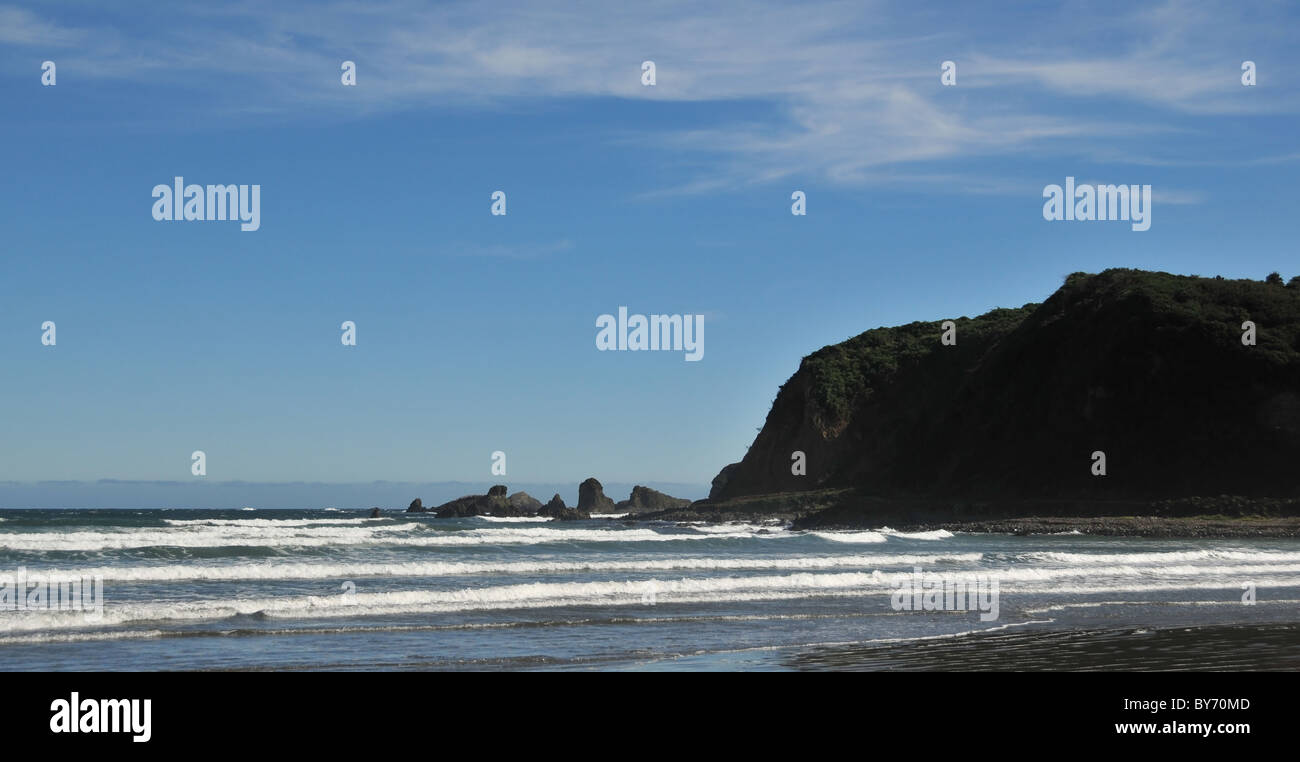Blue sky view of Pacific Ocean surf breaking on the beach and volcanic ...