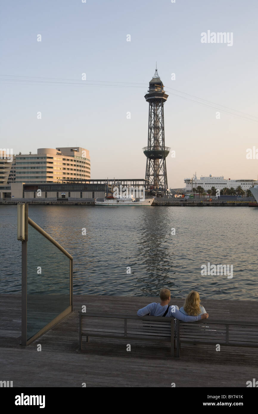Couple on bench at harbor and Montjuic Teleferico cable car tower ...