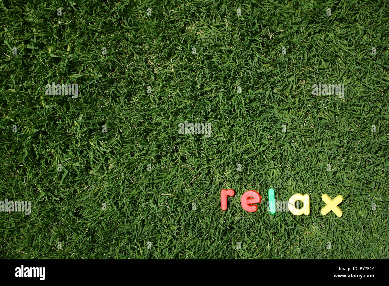 The word 'relax' spelled out in colourful plastic letters, on green ...