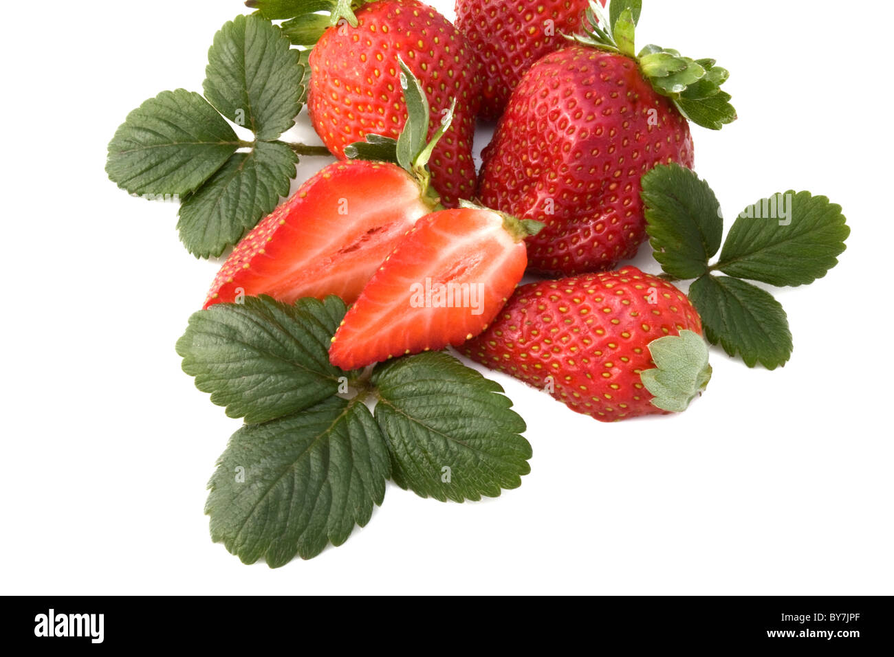 Red whole and cut strawberries on green strawberry leaves, isolated on ...