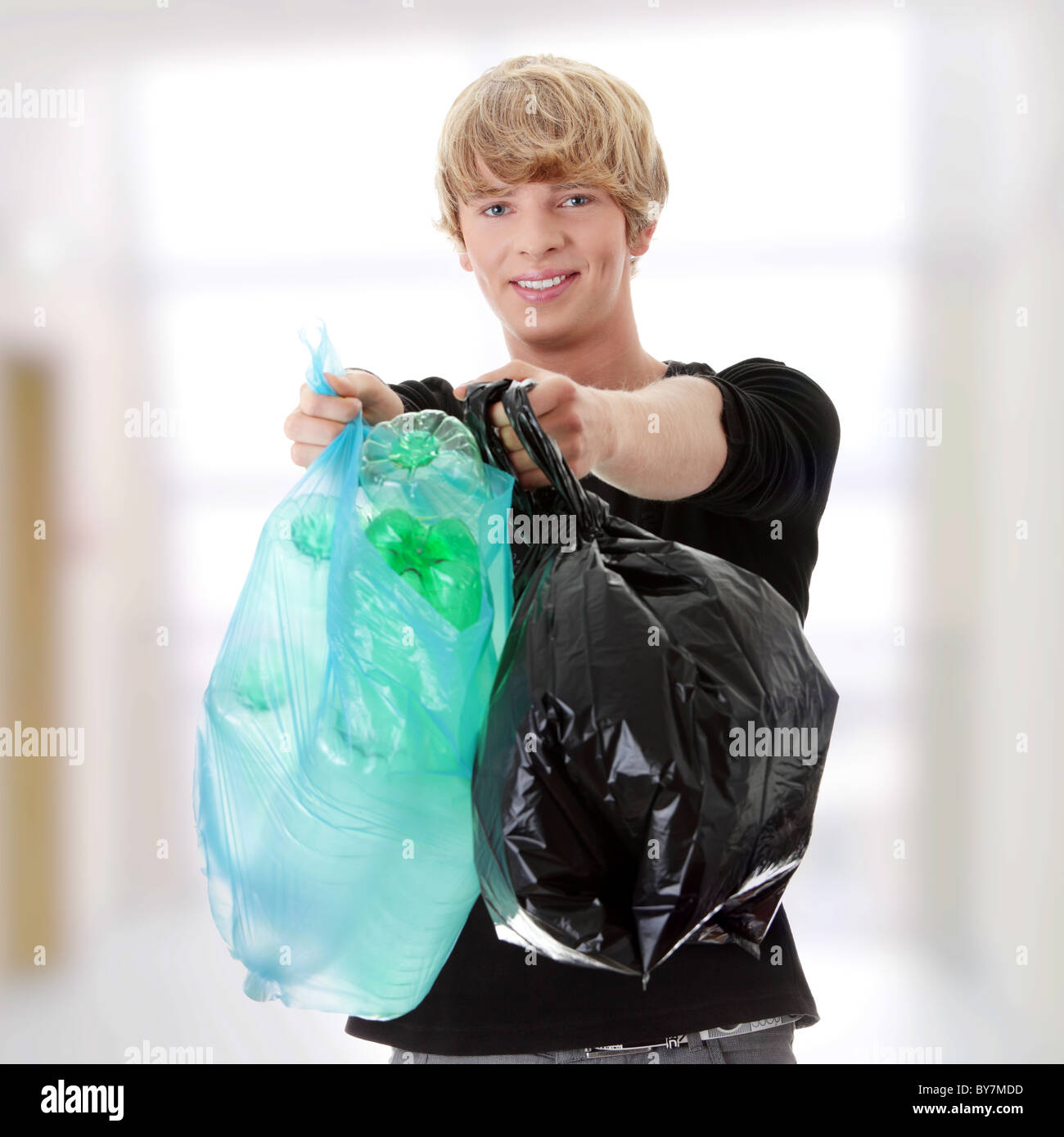 Young man carrying a plastic trash bags full with empty recyclable ...