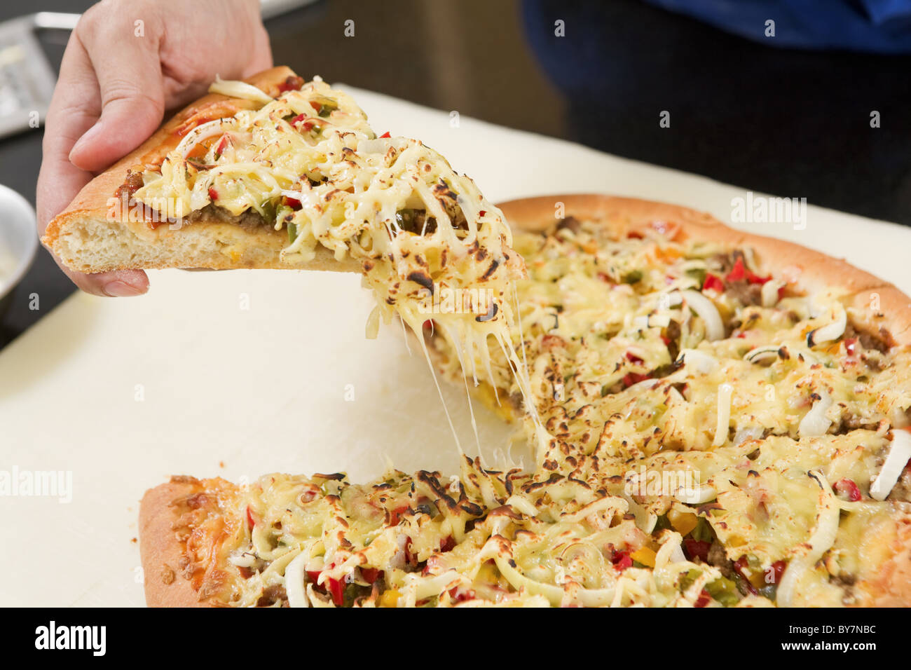 Hand grabbing a slice of pizza, melted cheese Stock Photo - Alamy