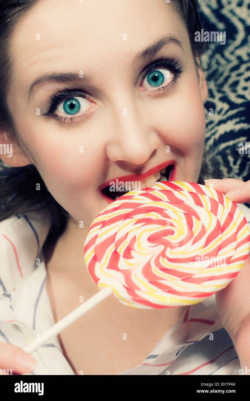 Portrait of young woman biting sugar candy Stock Photo - Alamy