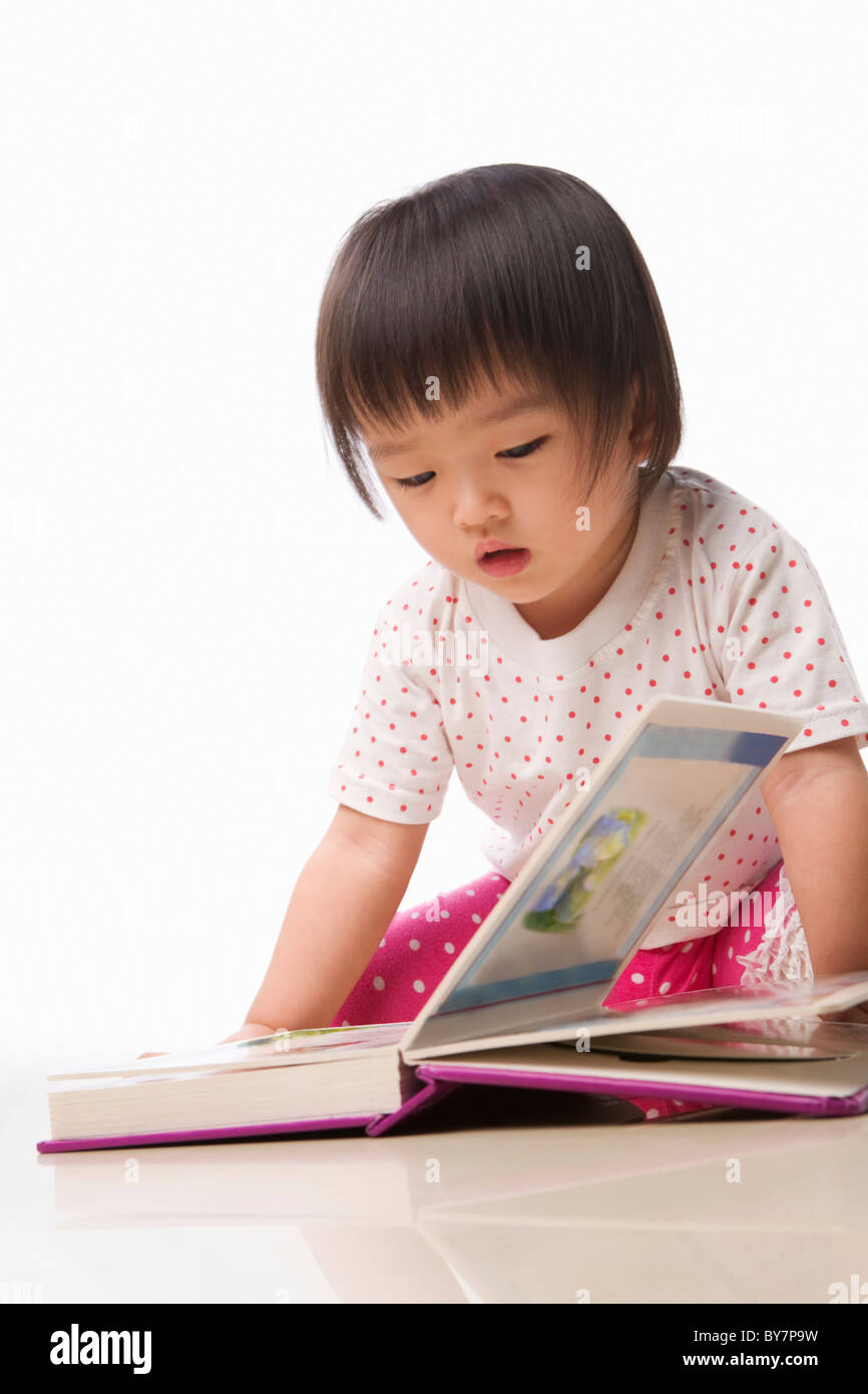Litlle Asian girl reading book alone on floor Stock Photo - Alamy