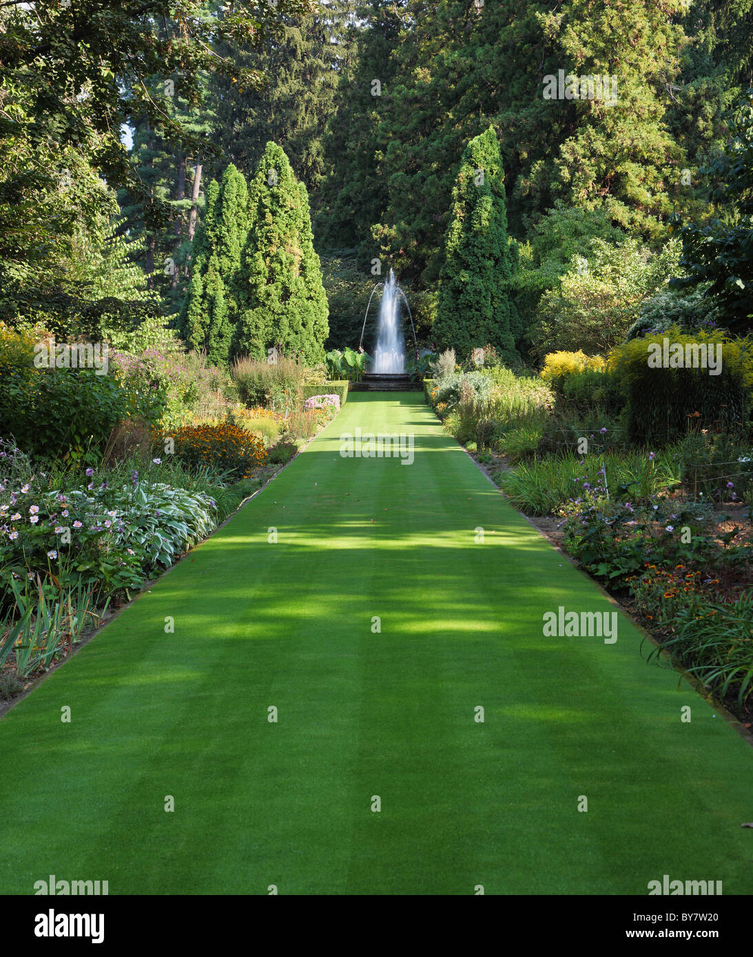Magnificent park. Green grass road to the charming fountain Stock Photo ...