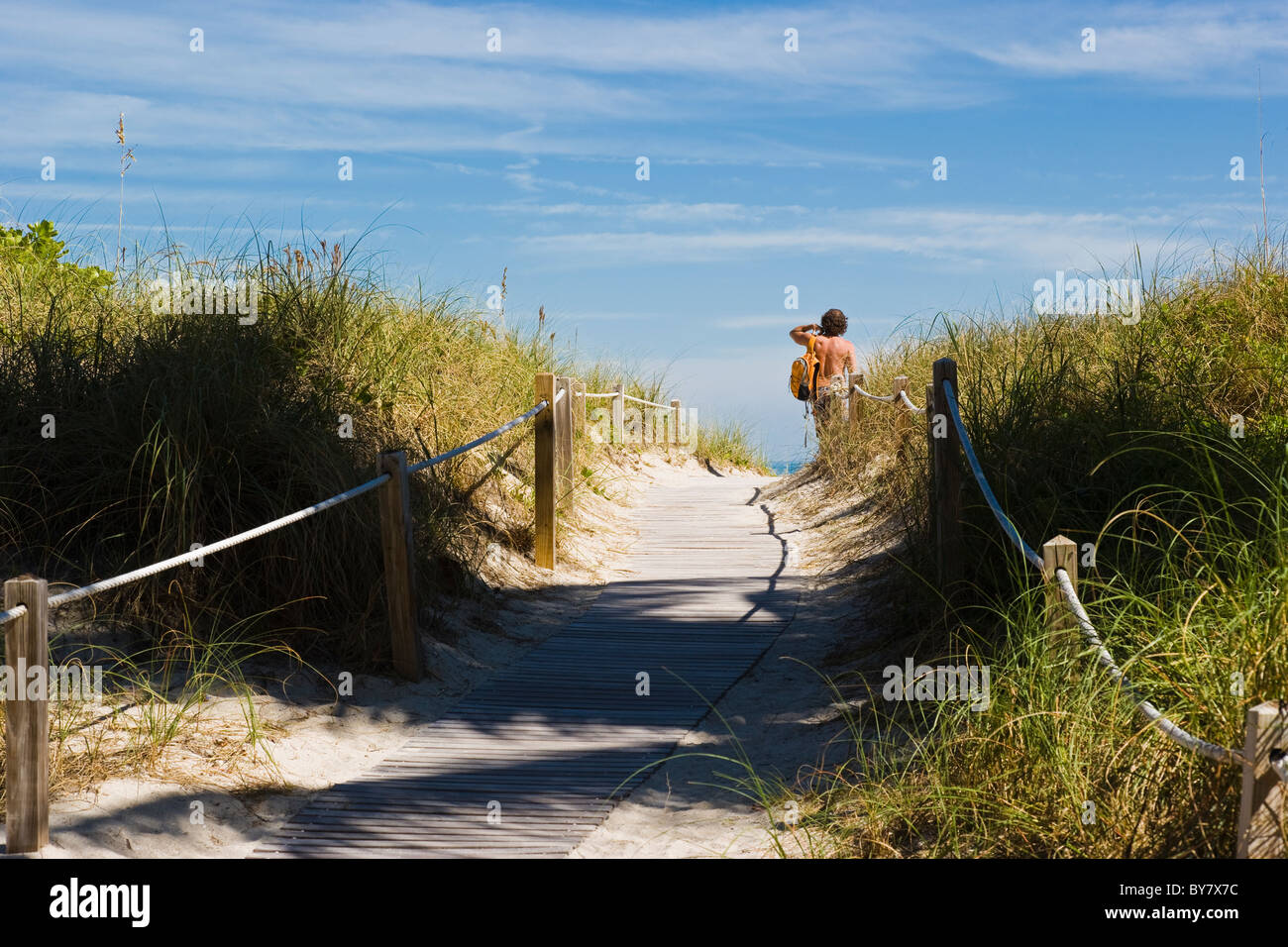 Man with back pack walking on path to beach, Miami Beach, Florida, USA ...