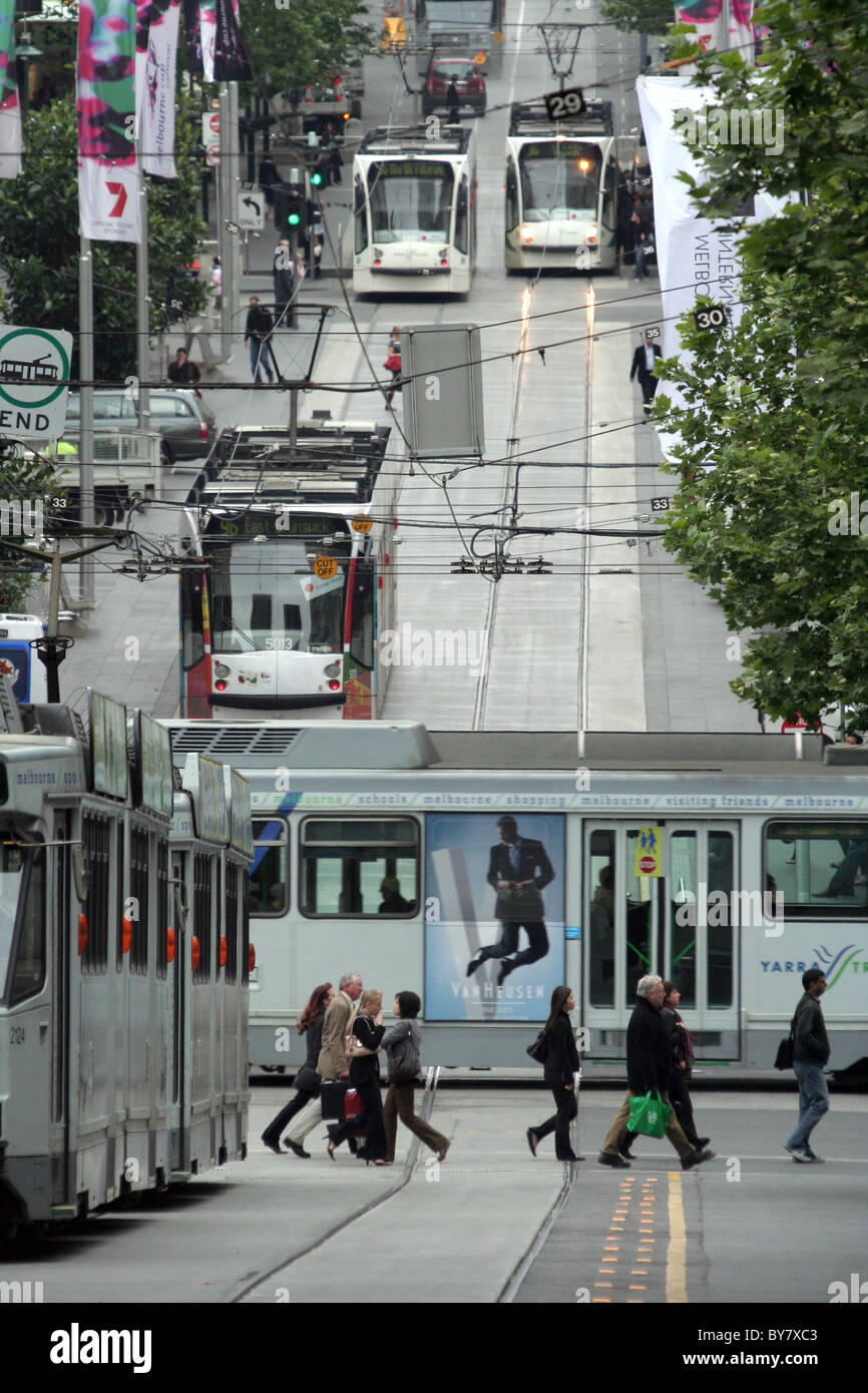 View along a busy street with many trams (light rail) and pedestrians ...